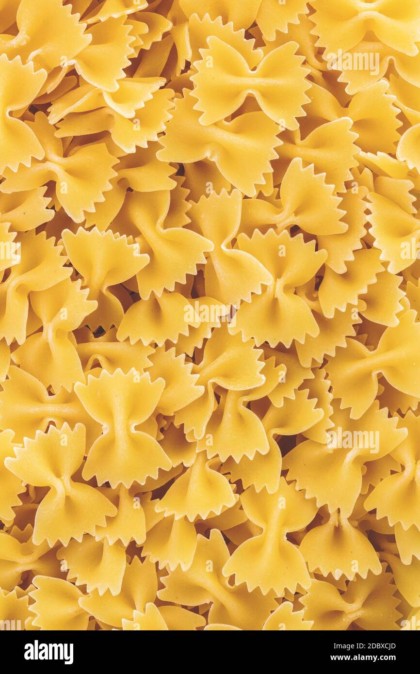 Italian pasta vertical background. Uncooked "bow-tie pasta" (farfalle ...