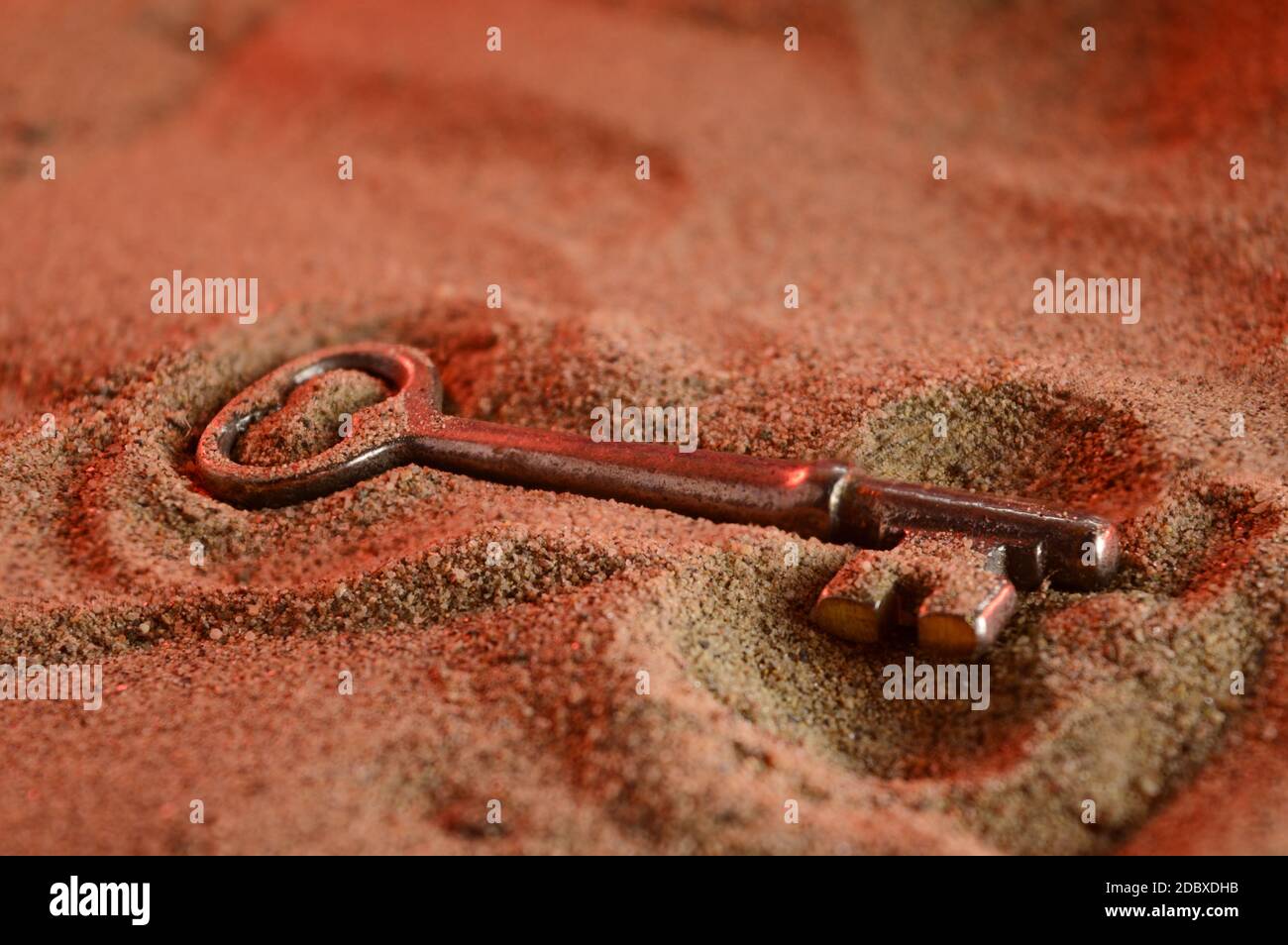 An ancient skeleton key is revealed at the surface of a sandy terrain ...