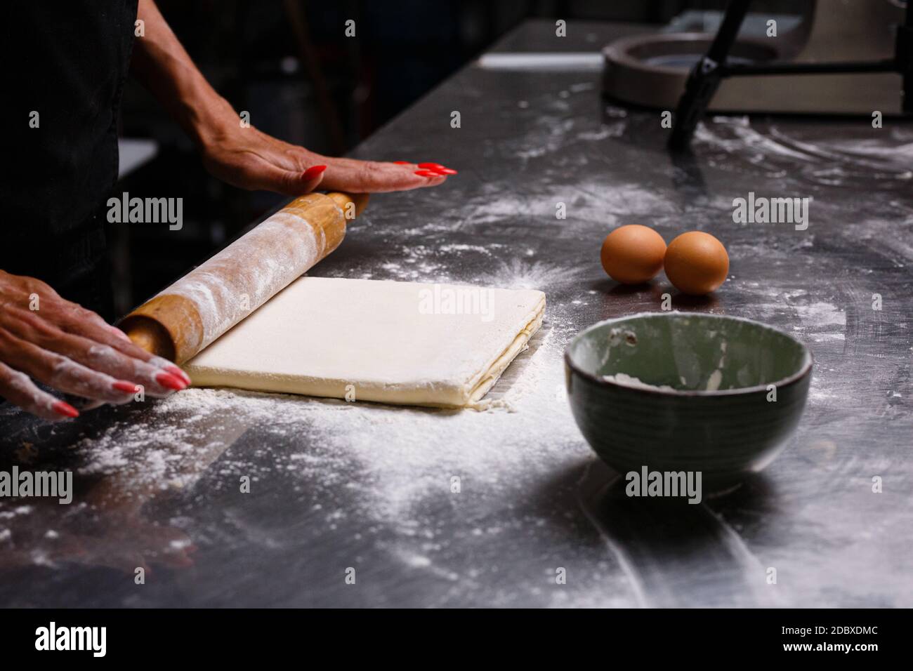 The chef prepares pastries in a professional kitchen. Knead the dough ...