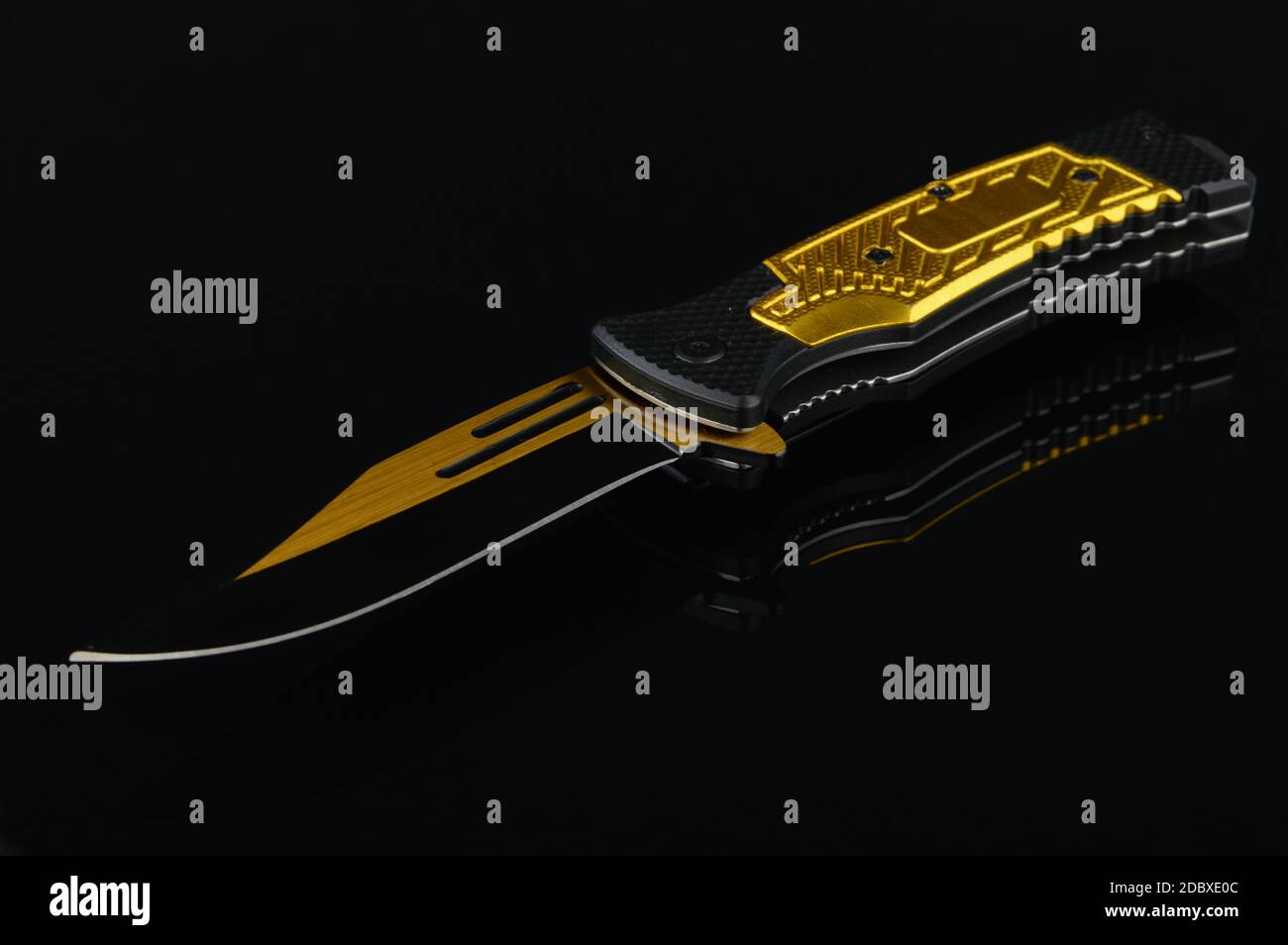 A black and gold pocket knife over a reflective surface Stock Photo - Alamy