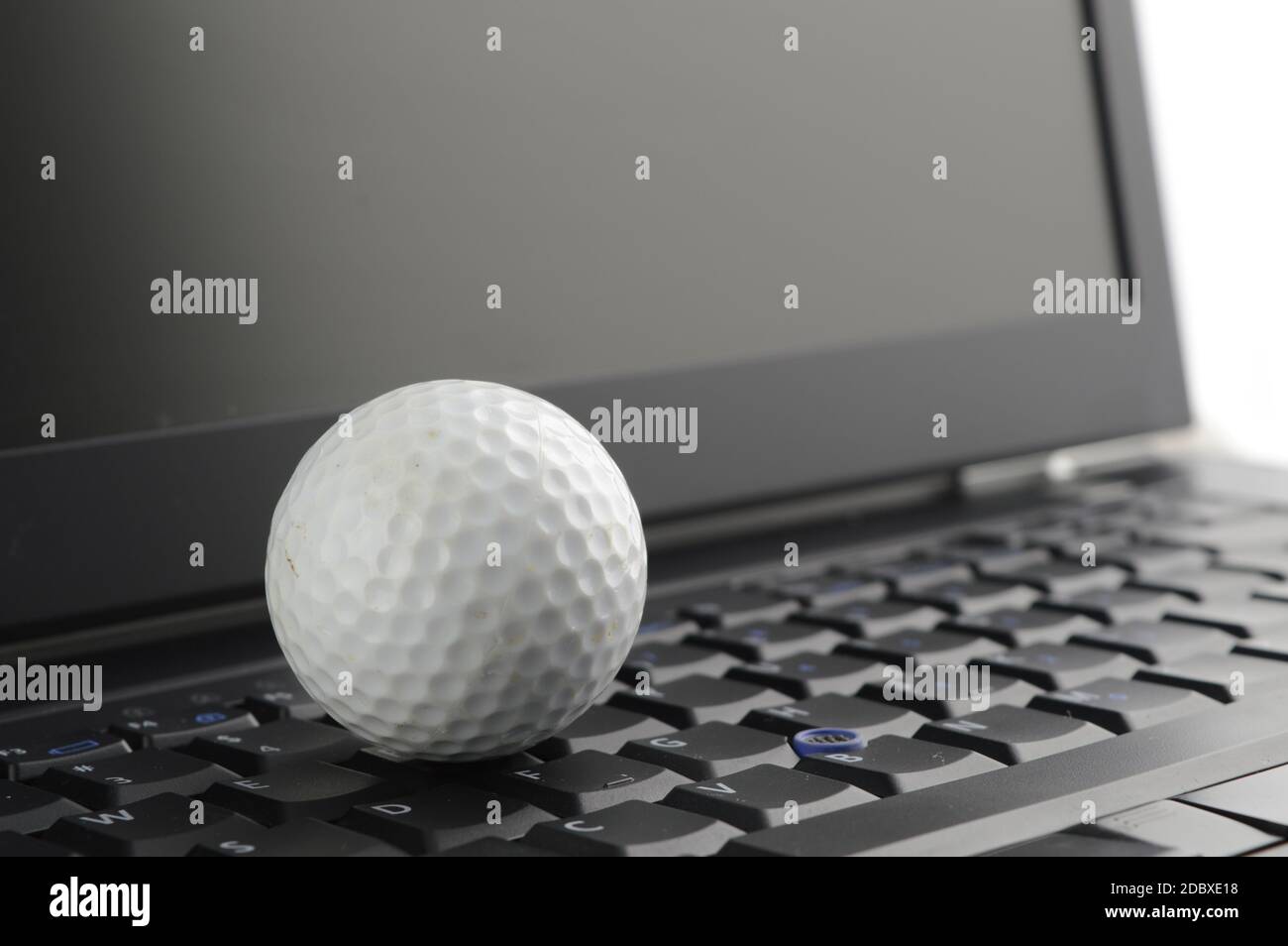 A golf ball on top of a laptop to make a descision of work or play ...