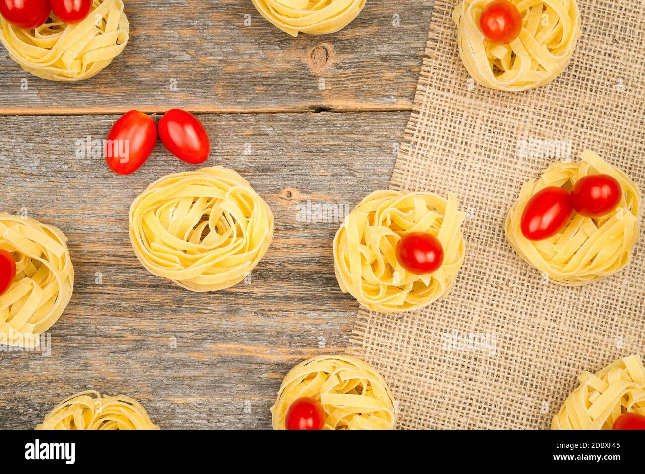 Close up of nests of tagliatelle noodles with egg-shaped mini roma ...