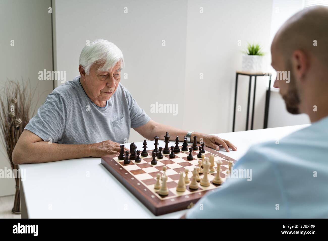 Elderly Senior Playing Chess With Caregiver At Home Stock Photo - Alamy