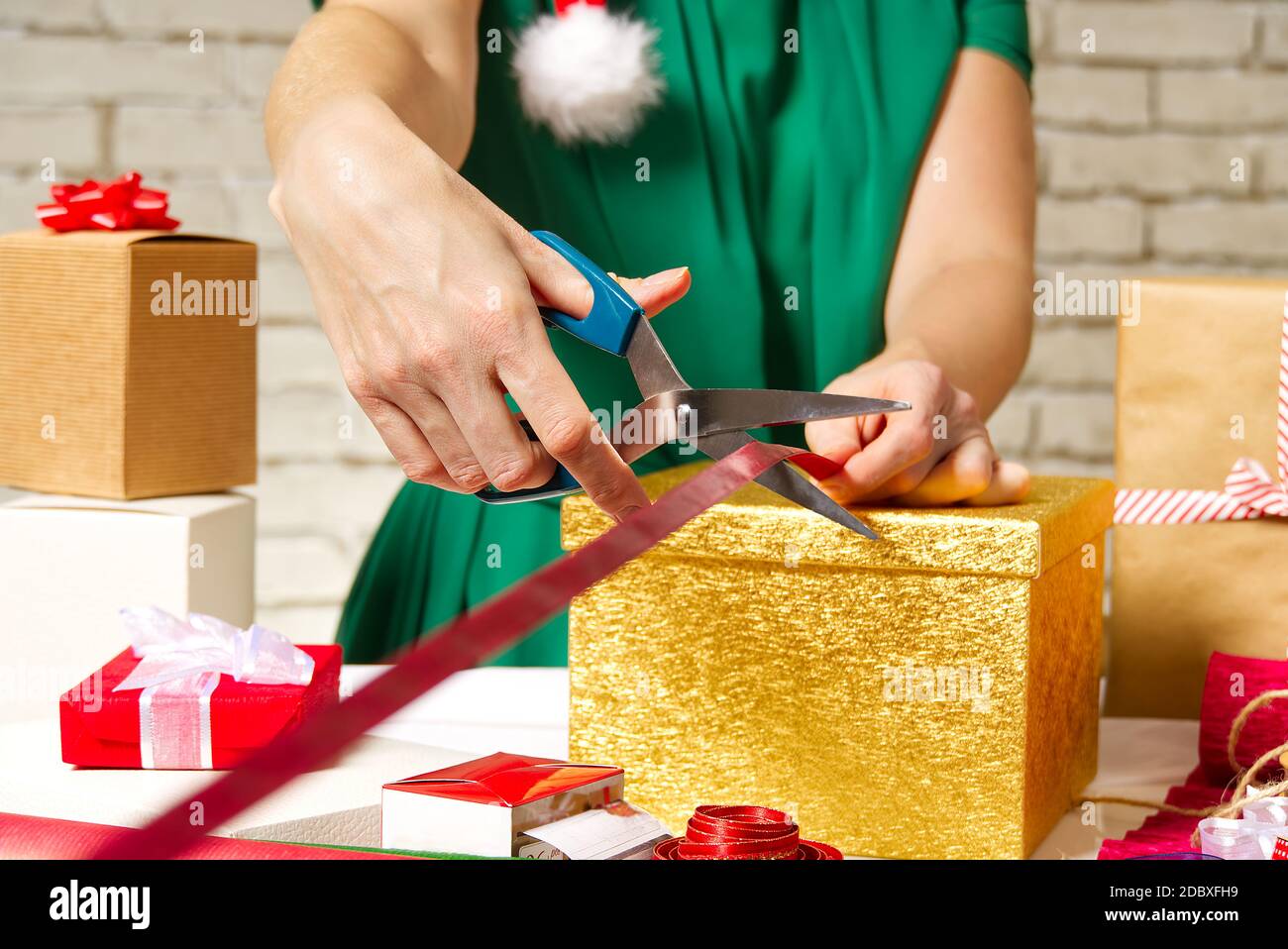woman hands packing a christmas gift in a gold box with a red ribbon ...