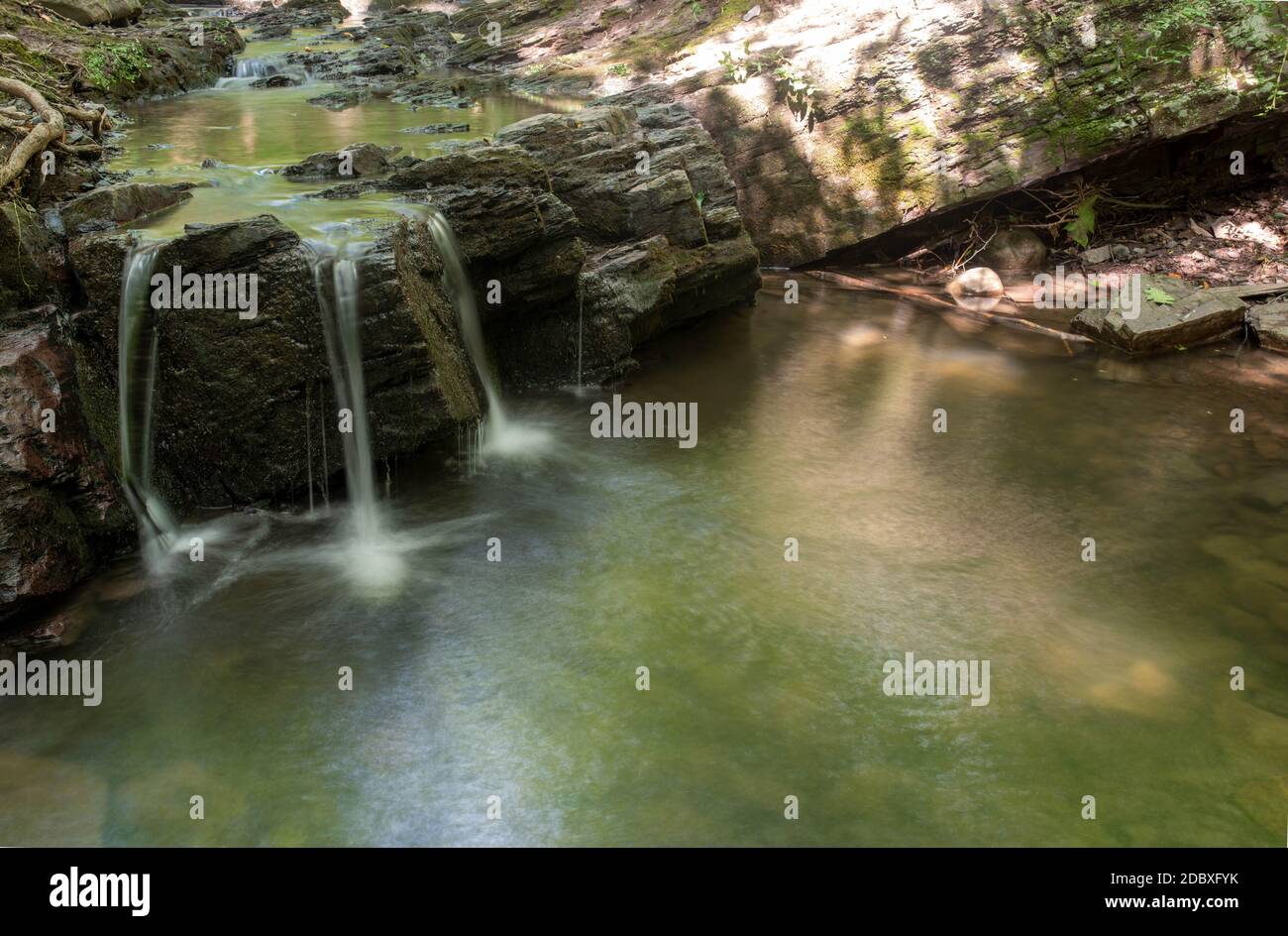 Full frame image of forest waterfall cascading over an ancient rock ...