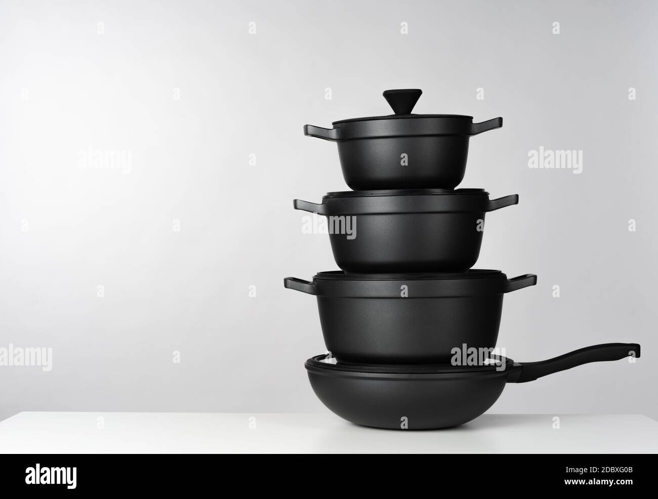 Black cooking pots on grey background front view Stock Photo - Alamy