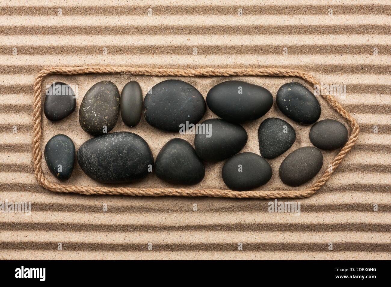 Pointer made of rope with black stones, lying on the striped sand Stock ...