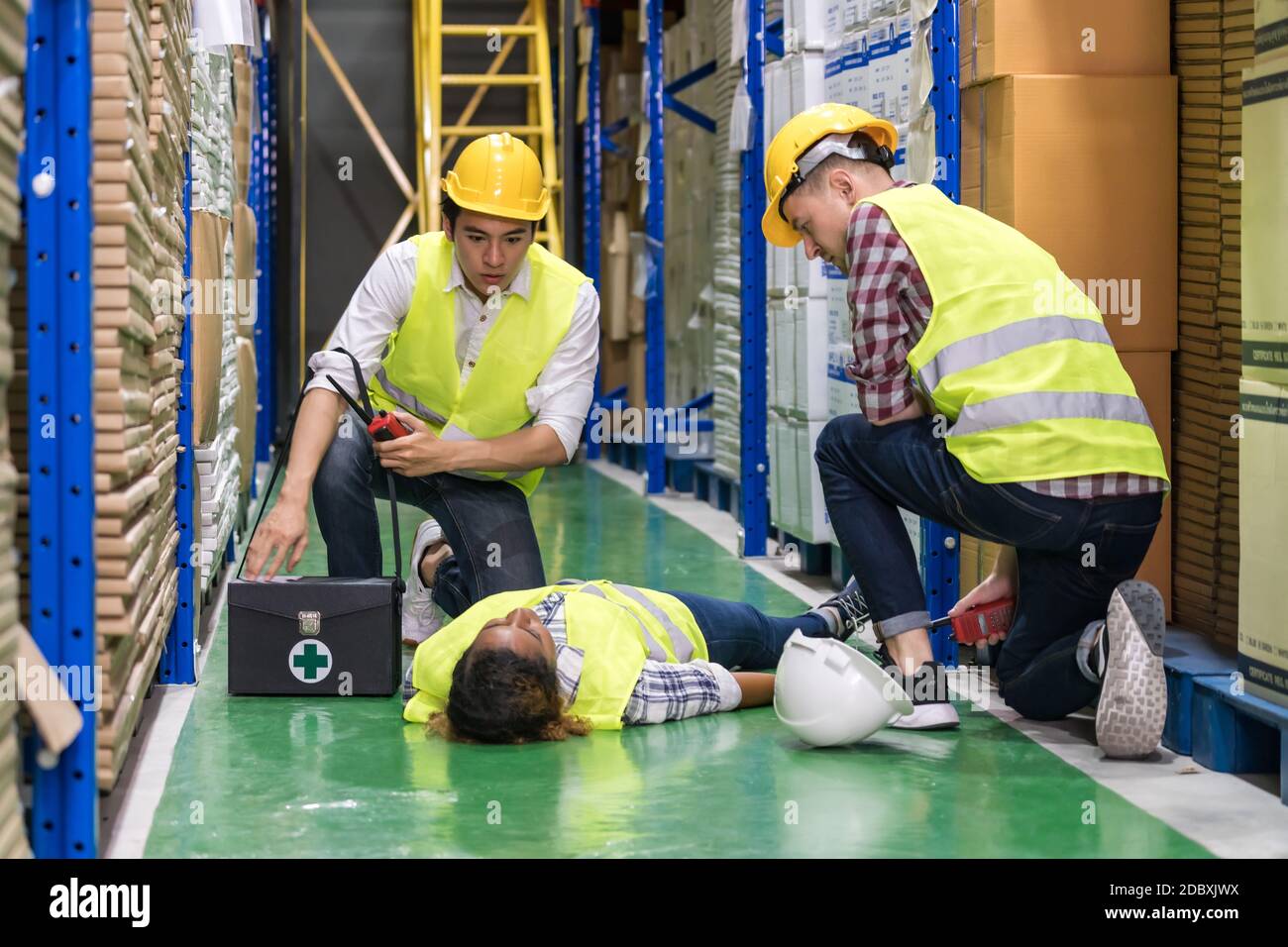Warehouse worker do first aid to his colleague lying down on warehouse ...