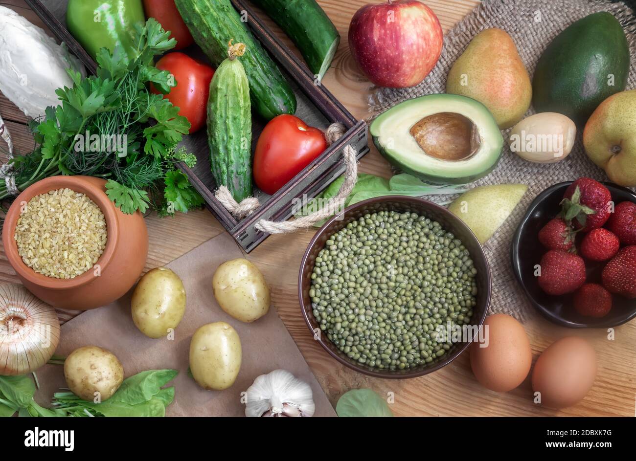 A variety of organic food items on the wooden table: fruits, vegetables ...