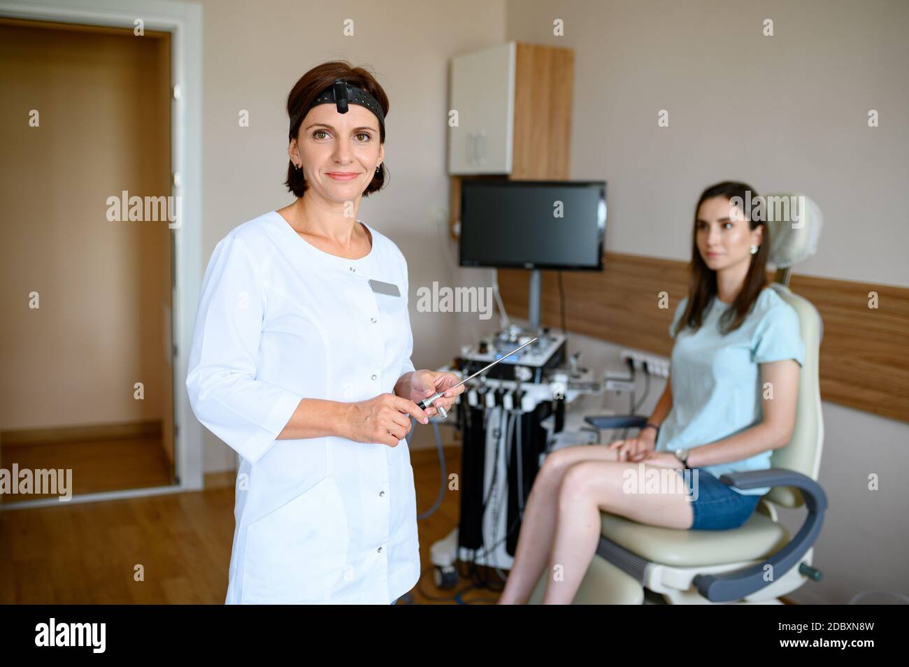 Smiling female laryngologist and patient in chair. Ear and nose ...