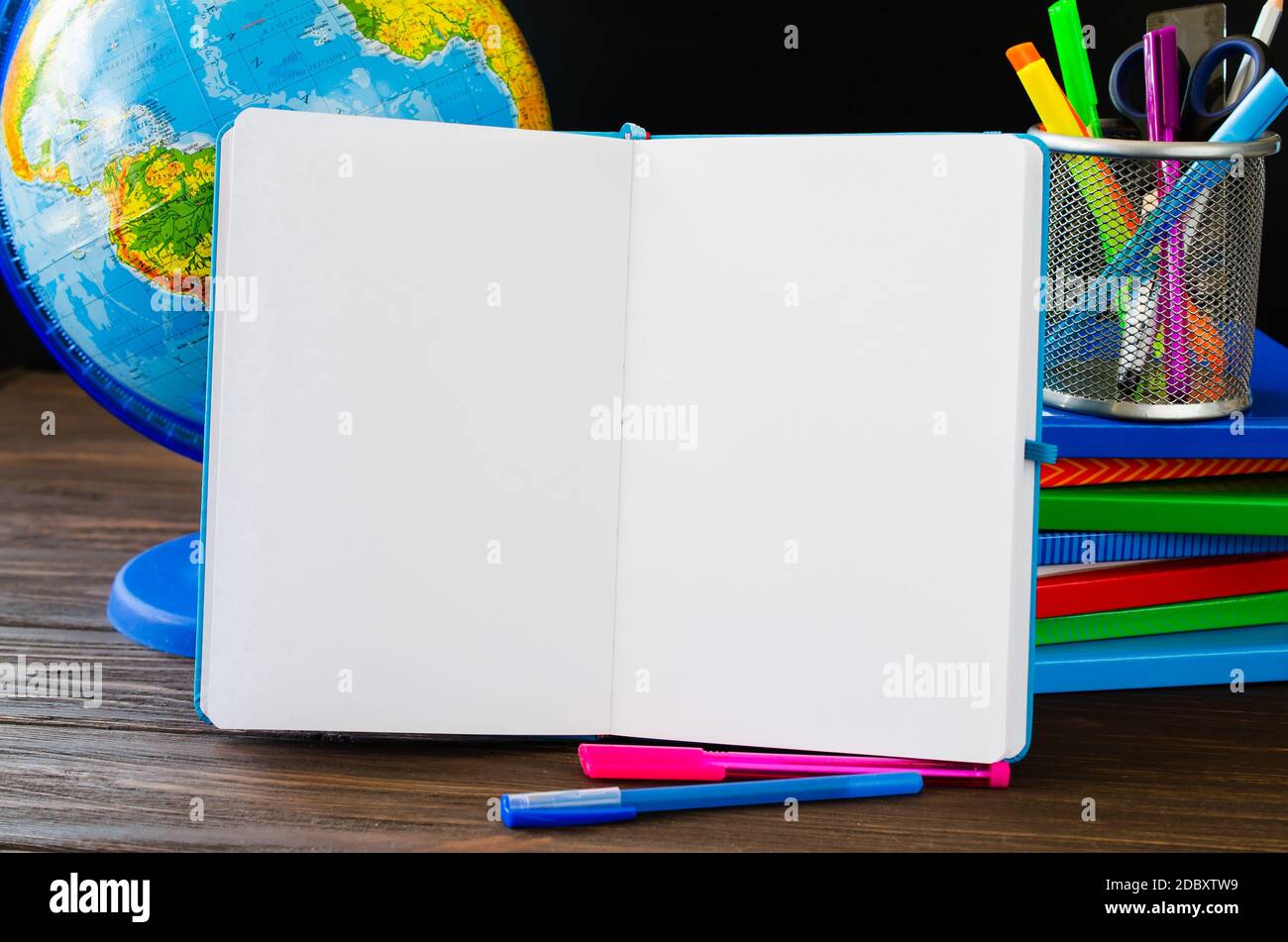 Back to school. Open empty notebook, stack of books, school supplies ...