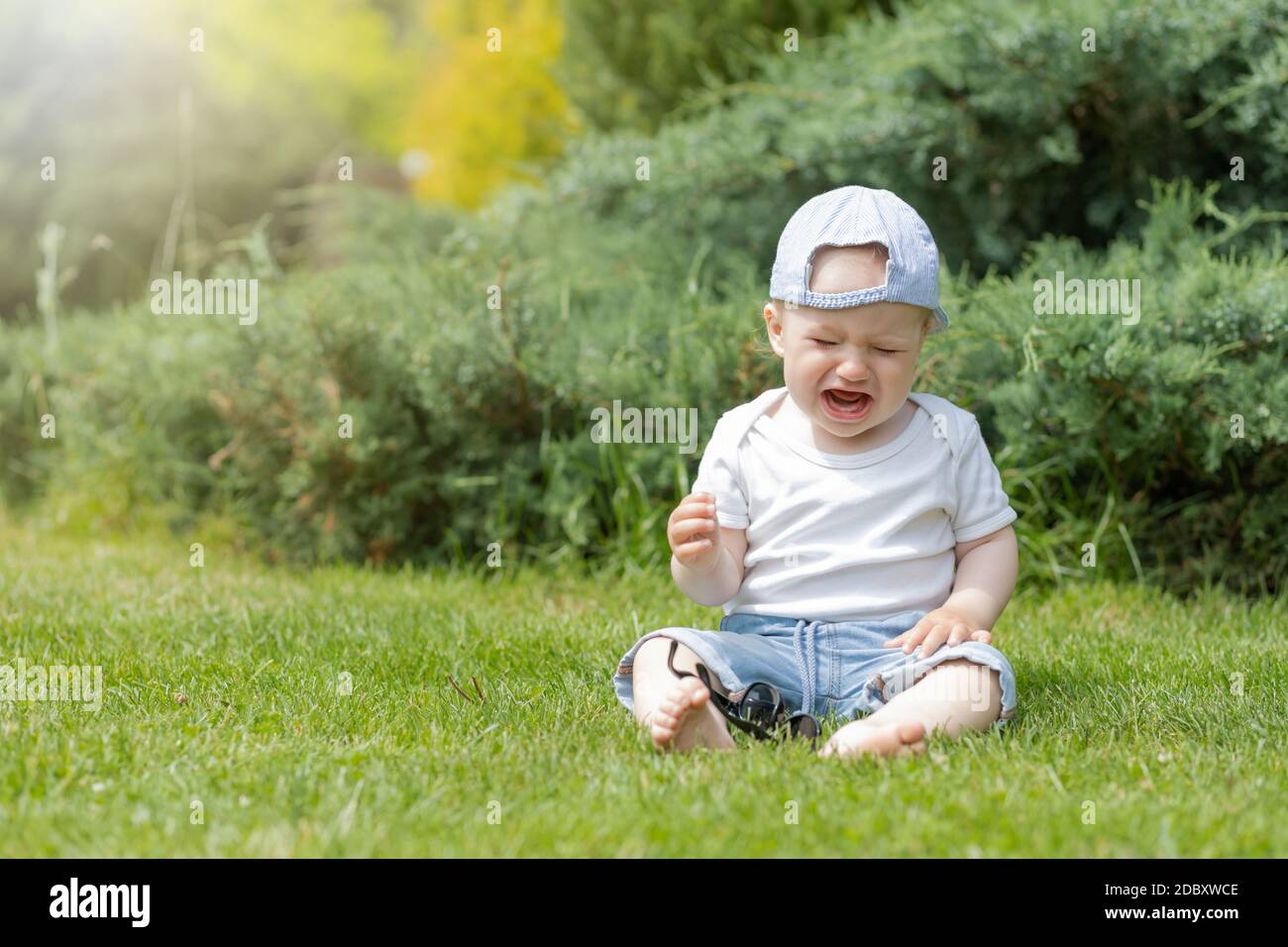 Little baby boy is crying sitting on the grass in the garden Stock ...
