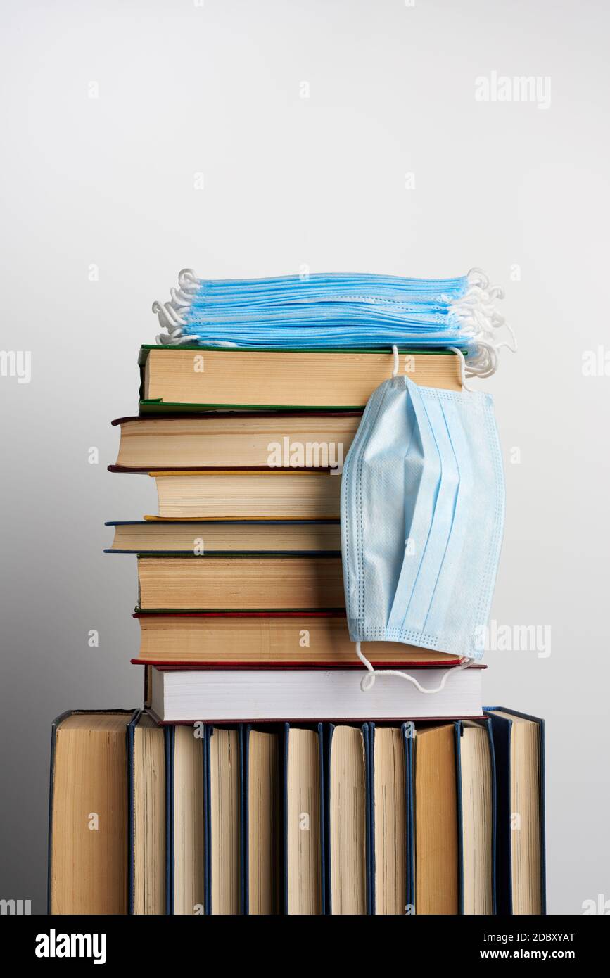 stack of various books and disposable medical masks on a white ...