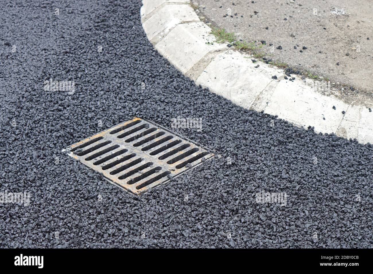 Storm drain and new asphalt at street corner Stock Photo - Alamy