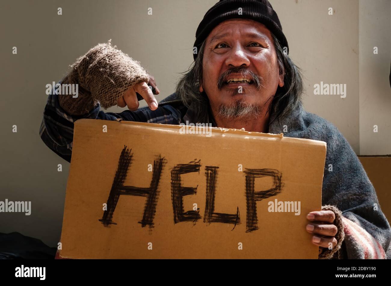Homeless man ask for help with his gesture and helping board, due to ...