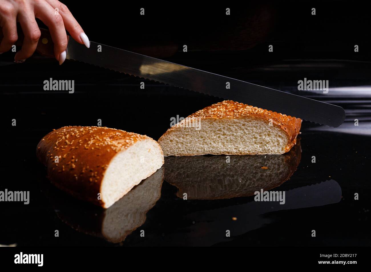 Homemade pastries. Crispy white bread cut with a knife. Photo on a black background Stock Photo ...