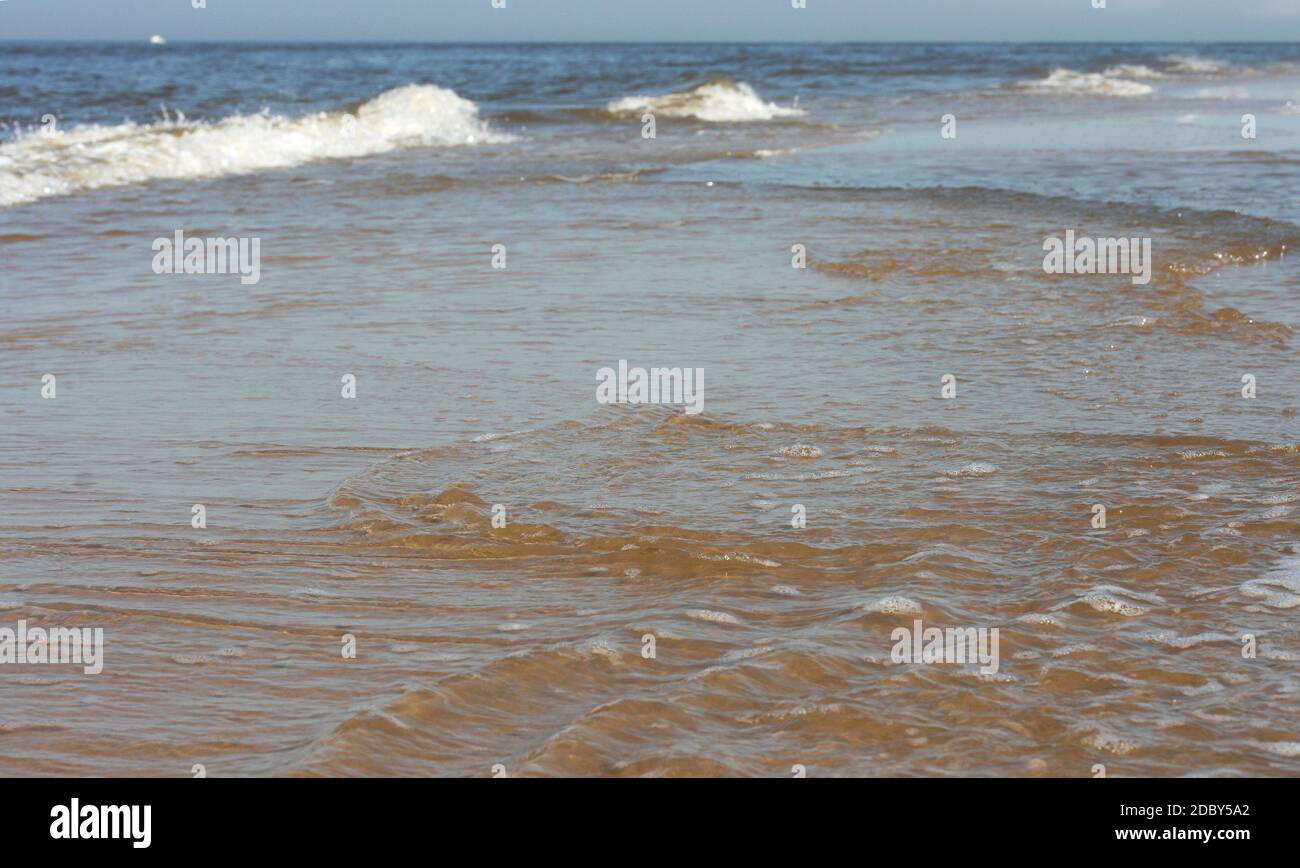 Waves with whitecaps flood the sandy beach Stock Photo - Alamy