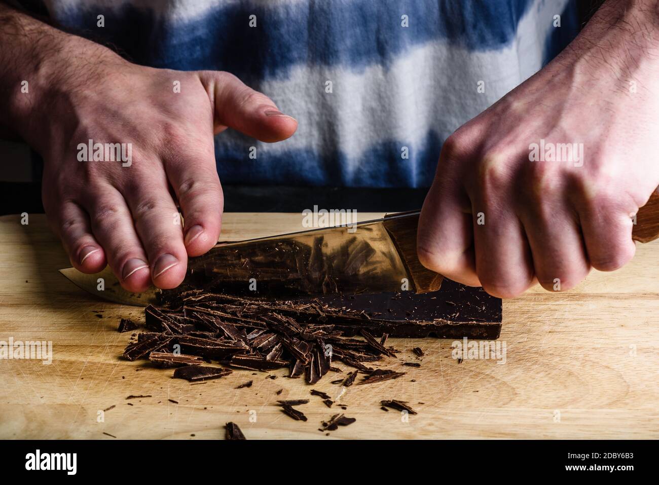 Roughly chopping dark chocolate bar with knife Stock Photo - Alamy
