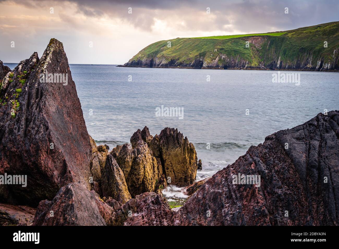 View on Dingle bay and peninsula from between rocks. Cliff with green ...