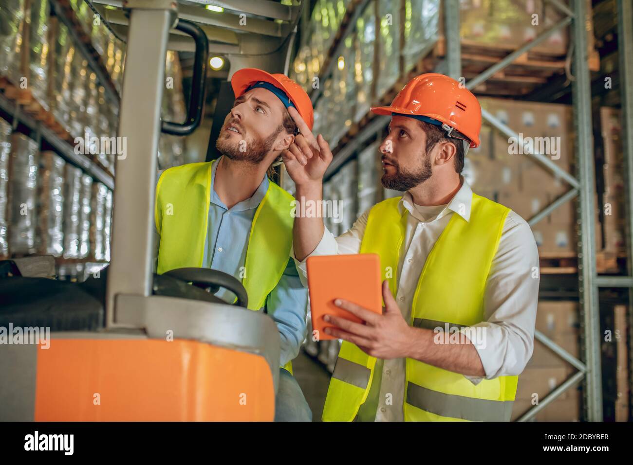 Two warehouse workers in helmets having a work conversation Stock Photo ...