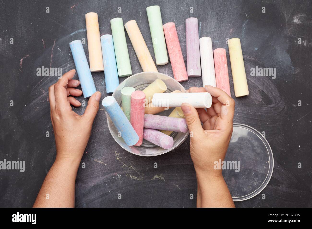multicolored chalk in a plastic bucket on a black background, female ...