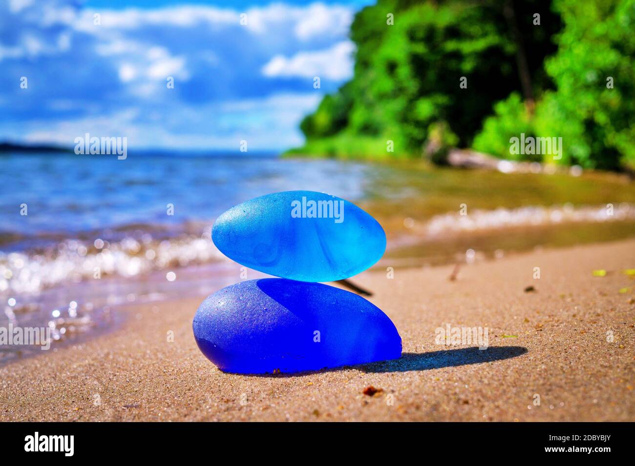Two smooth blue stones balanced on tropical beach with sea in ...