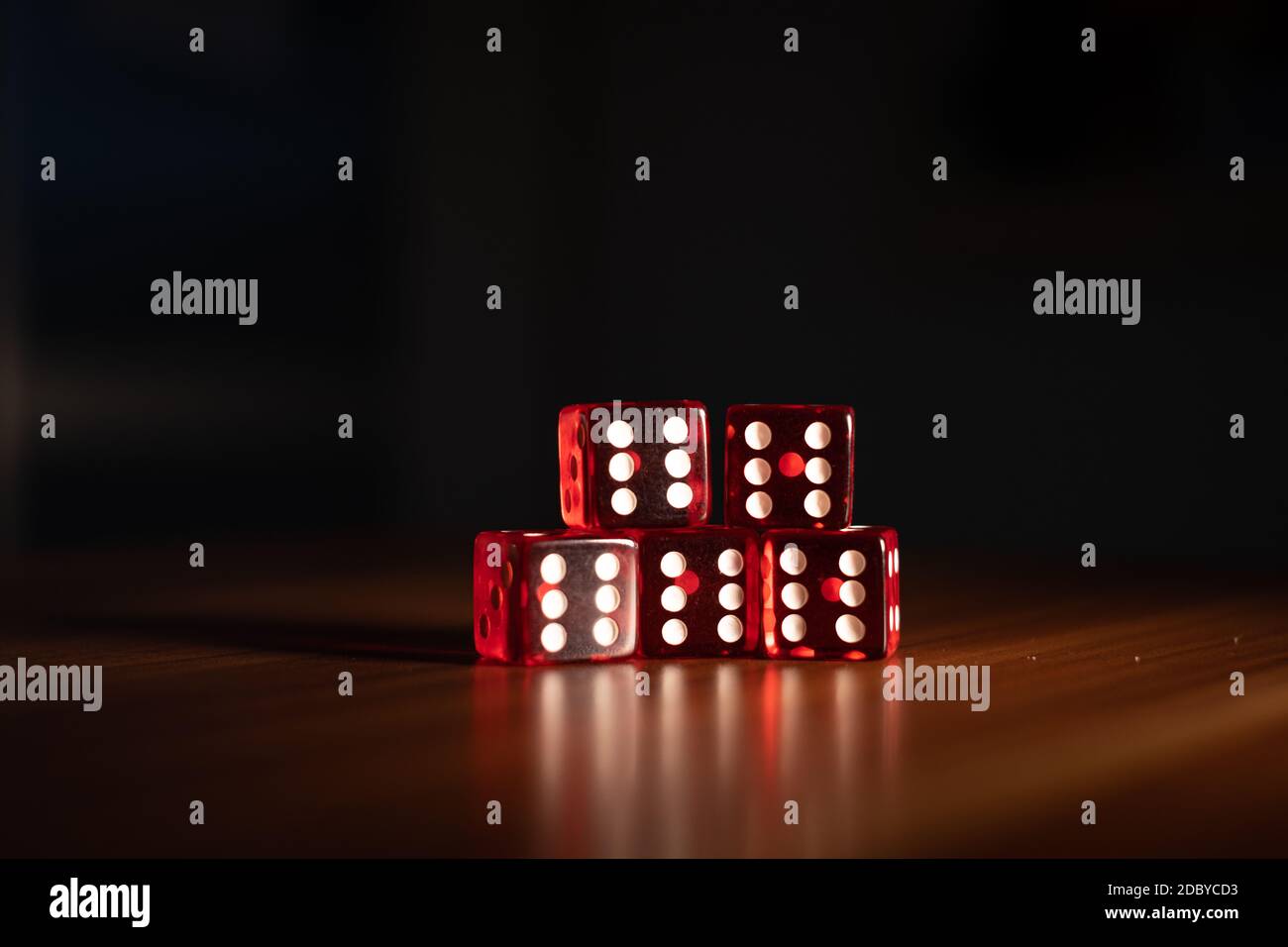 on a wooden plate there are five red dice next to each other Stock ...