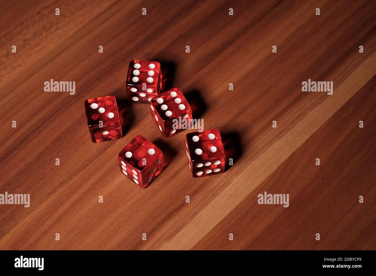 on a wooden plate there are five red dice next to each other Stock ...