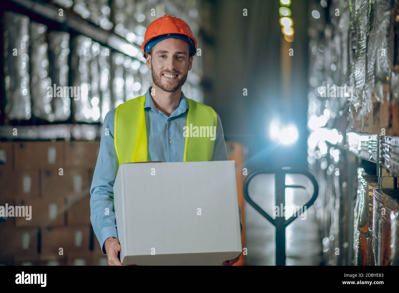 Young male worker carrying a box and smiling Stock Photo - Alamy