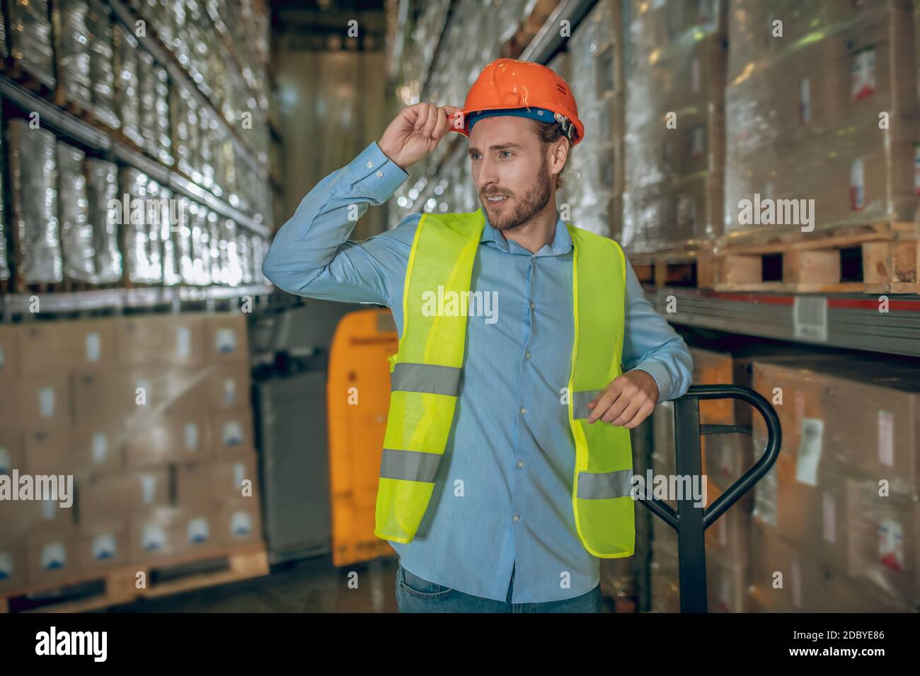 Young male worker standing near the loader and touching his helmet ...
