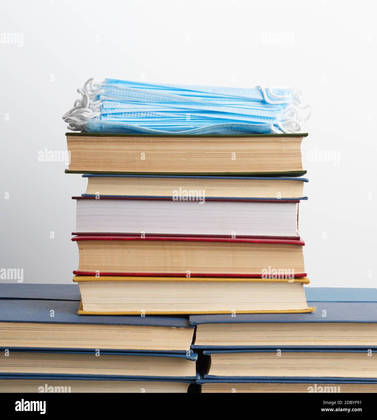 stack of various books and disposable medical masks on a white ...