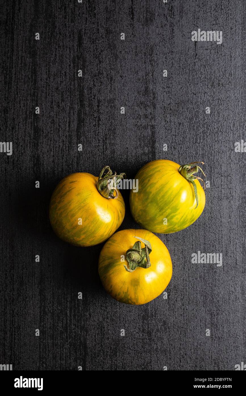 Green zebra tomatoes on black table. Top view Stock Photo - Alamy