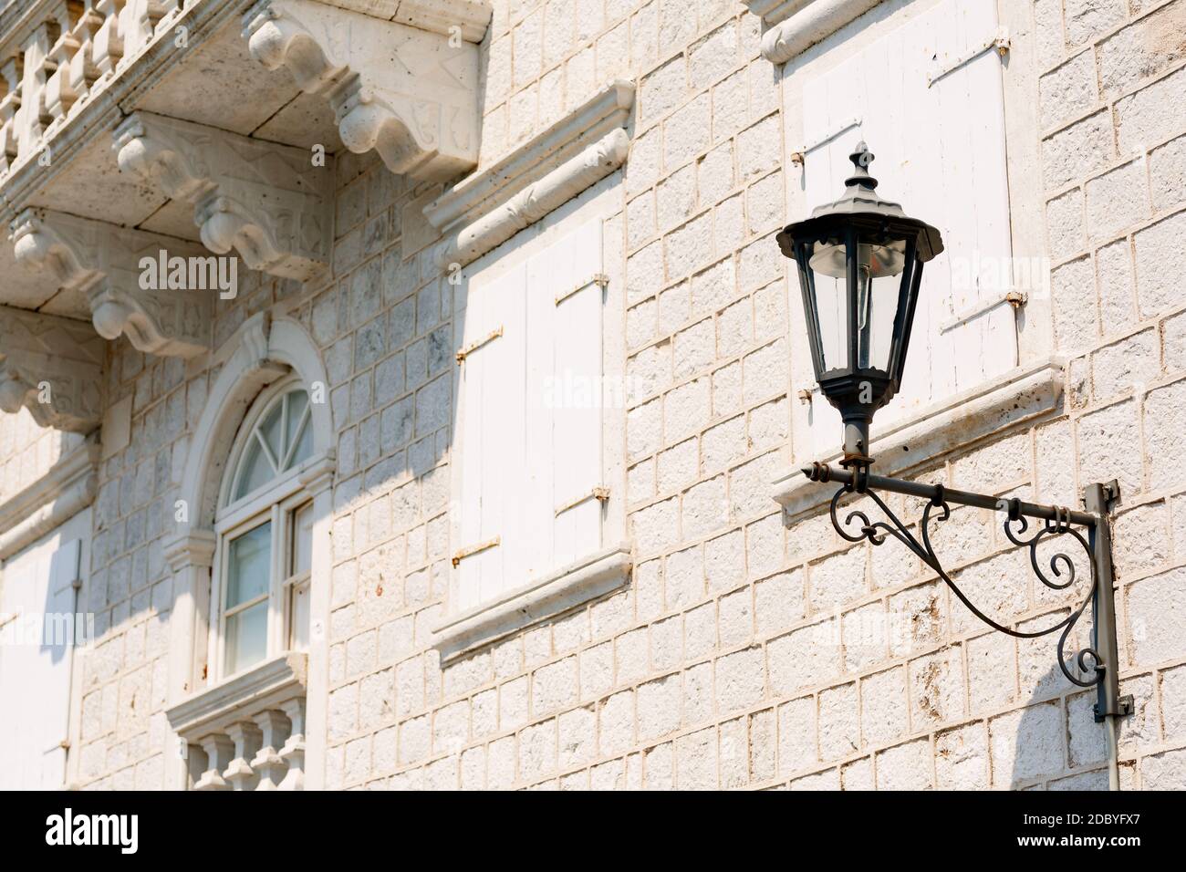 Close-up of a street lamp on the wall of a house under a balcony on a ...