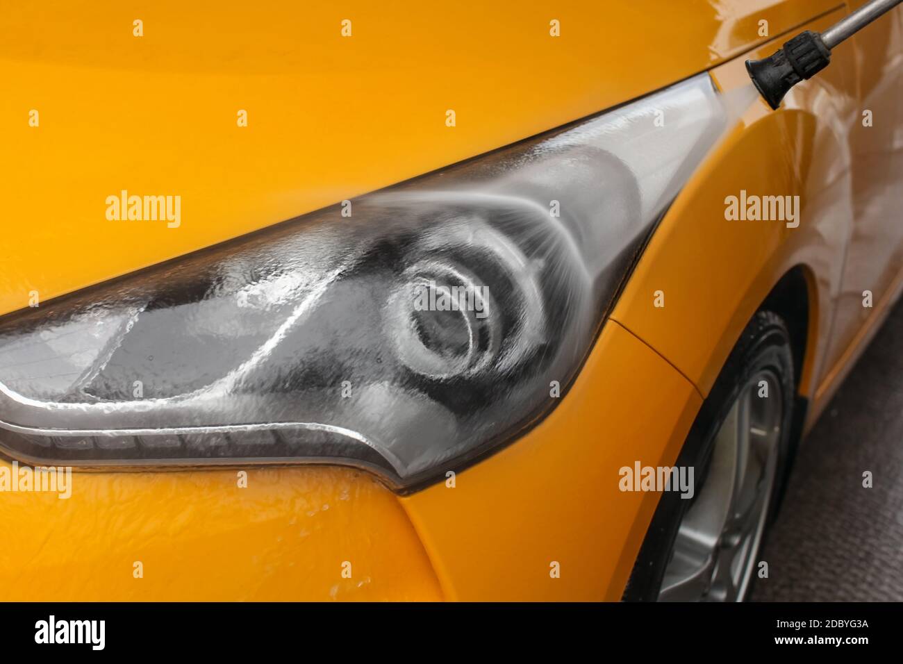 Detail on dark yellow car front light being washed with jet water in ...