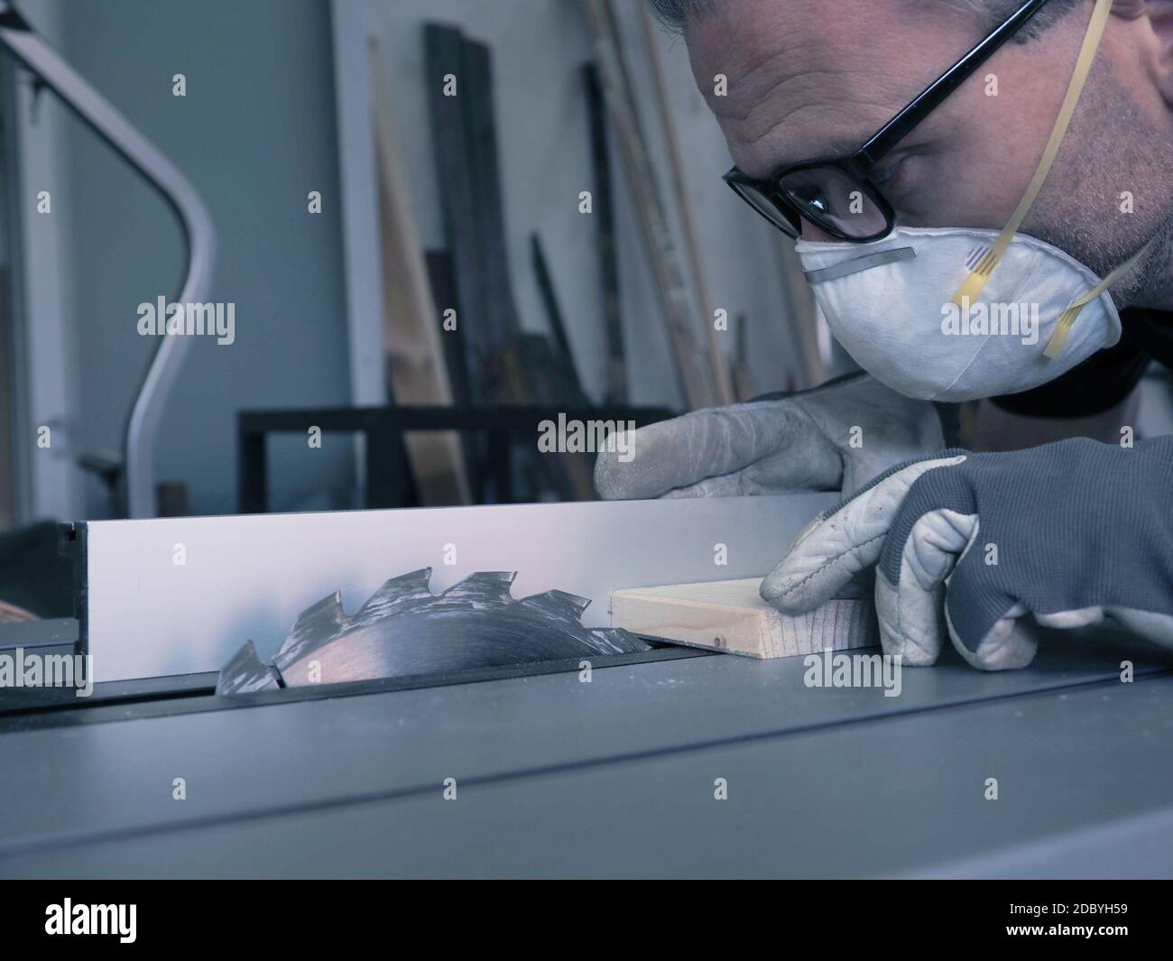 Man with a dust mask and goggles working on a circular saw ...