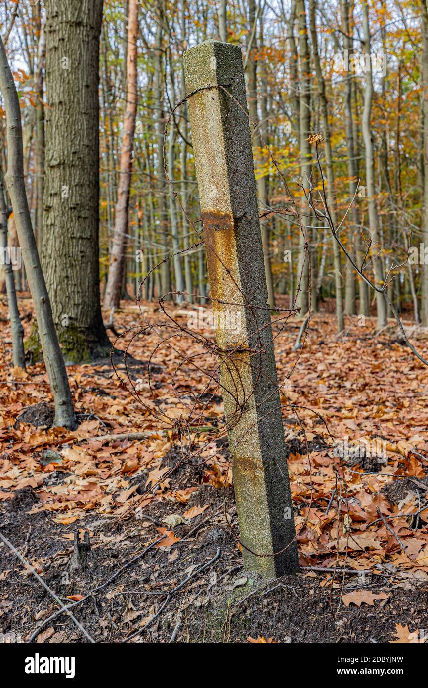 Old concrete post with broken, rusty and coiled barbed wire, near the ...