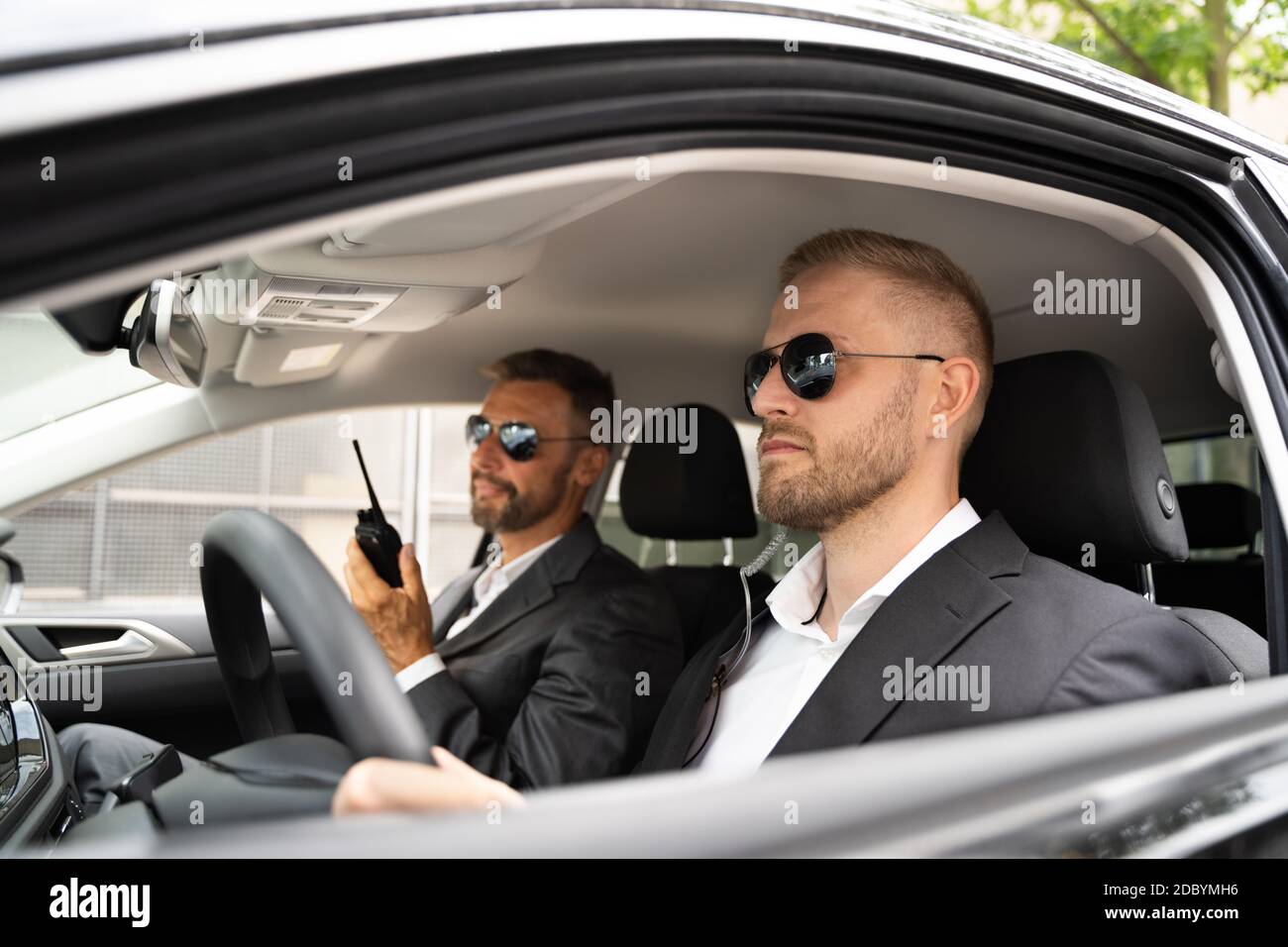 Security Guard In Sunglasses Inside Car Talking On Walkie Talkie Stock ...