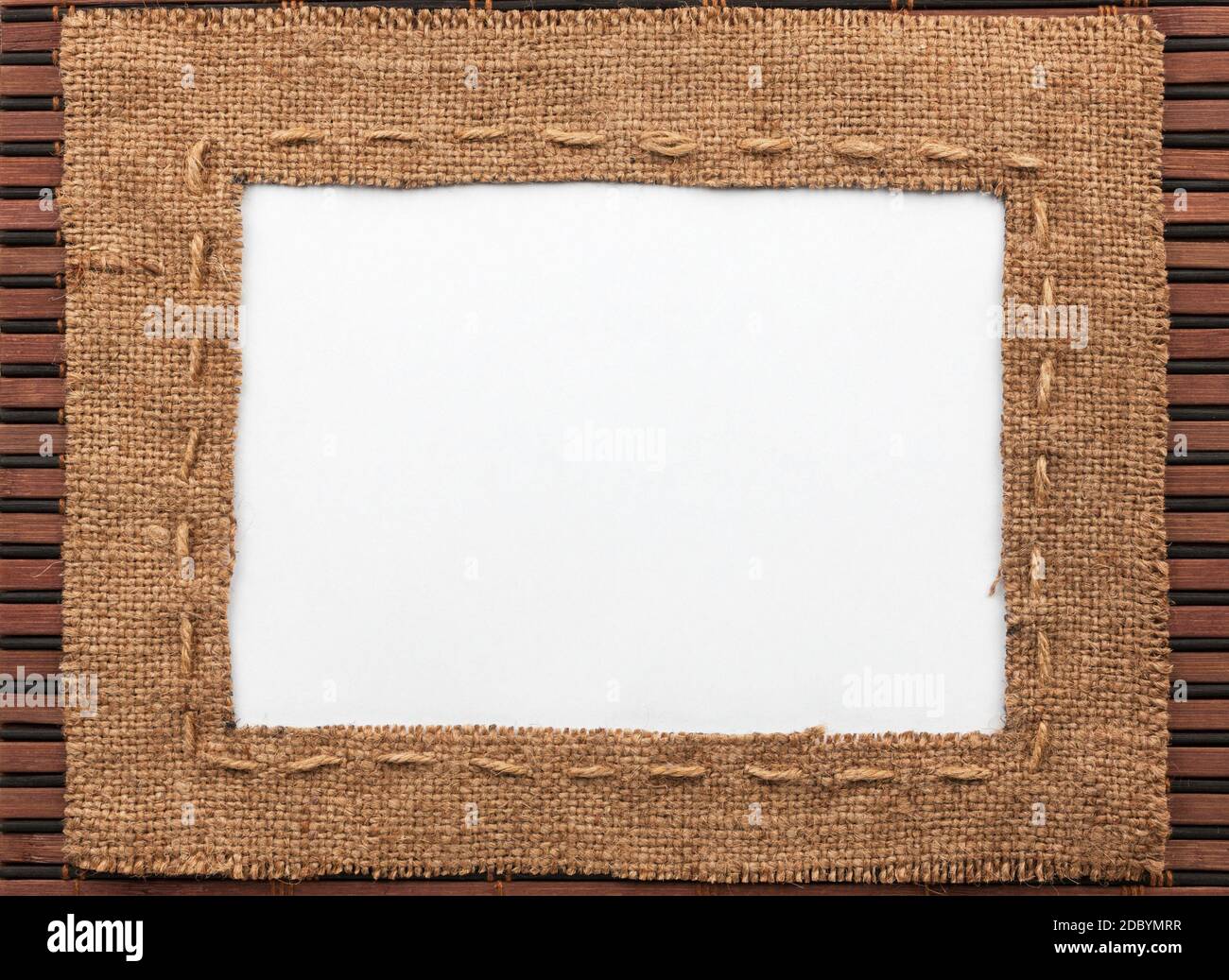 Frame made of burlap with white background lying on a bamboo mat, with ...