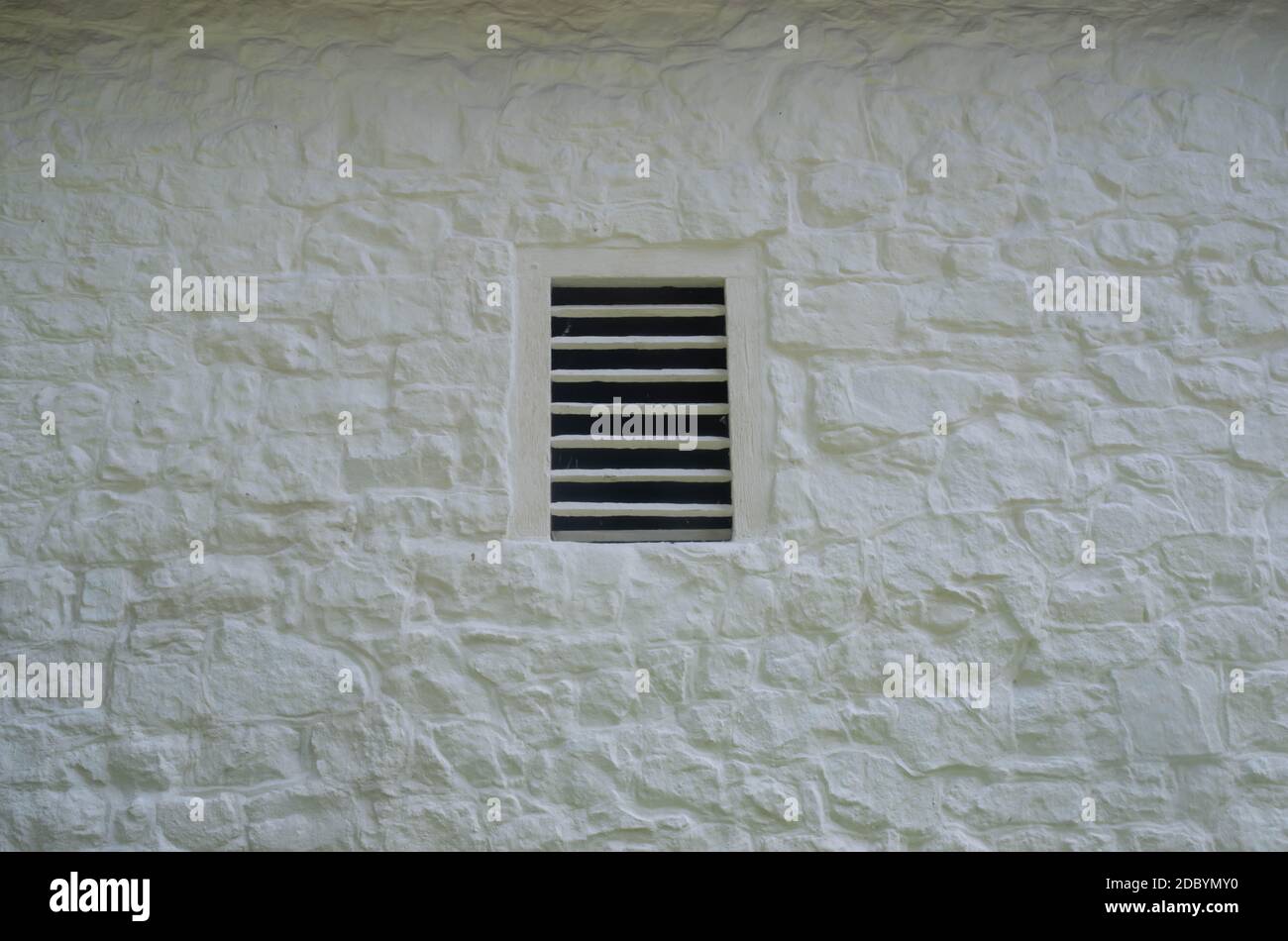 Old slatted ventilation window in a whitewashed stone wall on historic ...