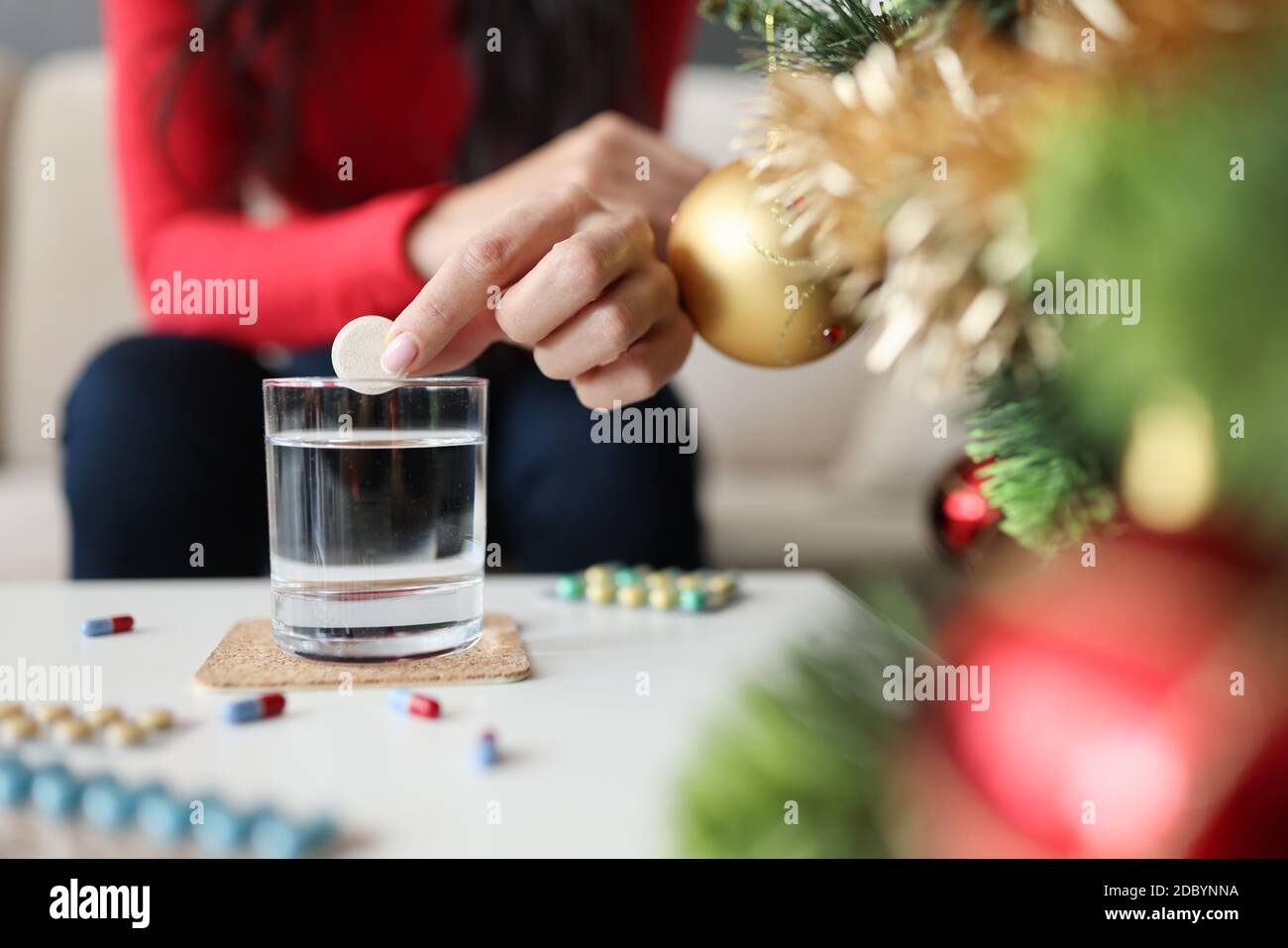 Female hand throwing effervescent soluble tablet into glass of water ...