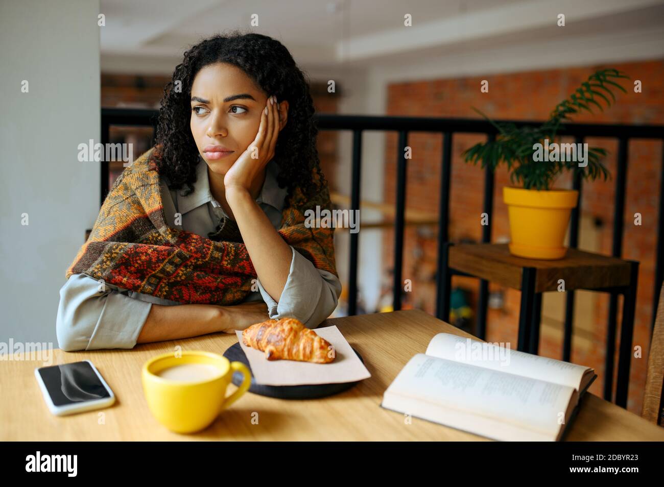 Tired female student at the table in cafe. Woman learning a subject in ...