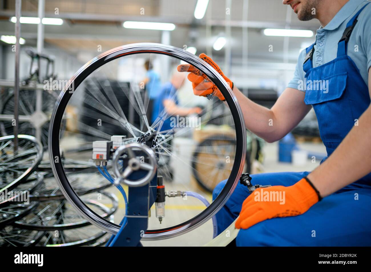 Male worker at the machine tool checks bicycle rim on factory. Bike ...