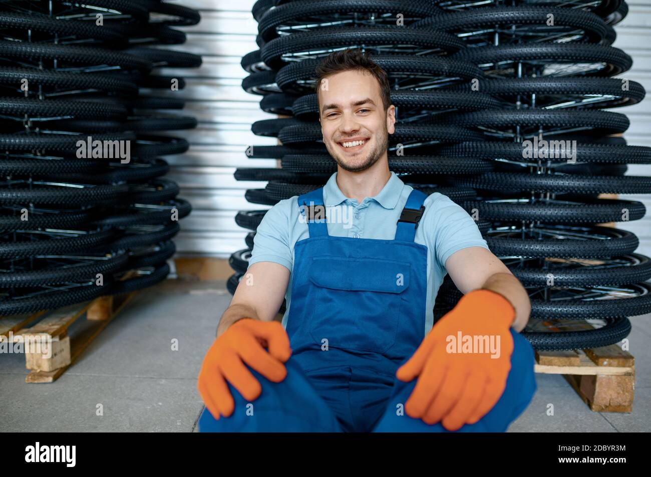 Male mechanic at the stack of bicycle wheels on a pallet on factory ...