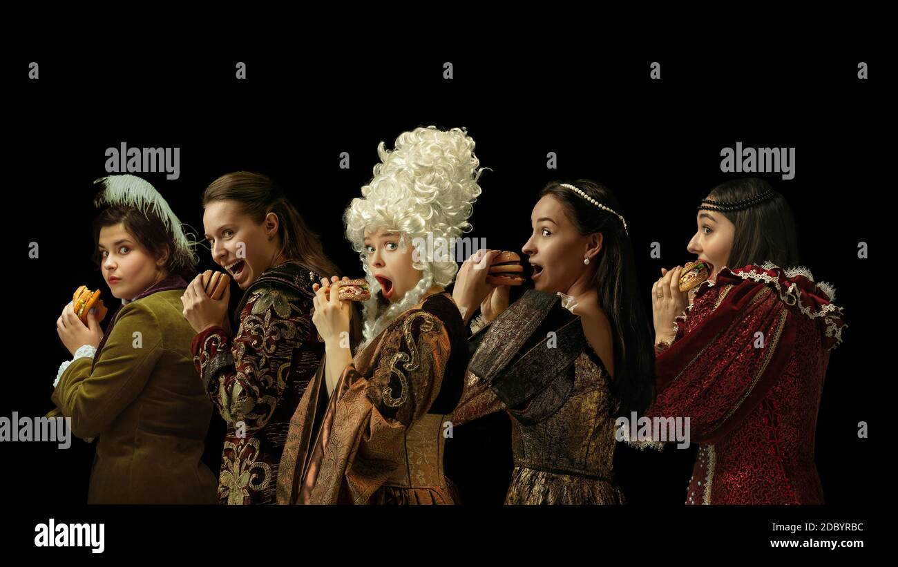 Medieval people as a royalty persons in vintage clothing eating burger ...