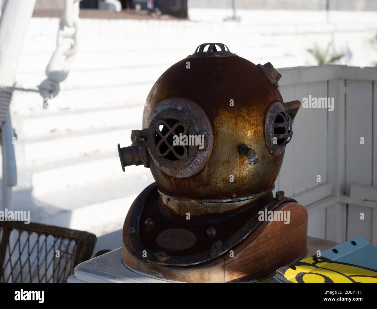 Decorative metal diving helmet on a rack against a background of white ...