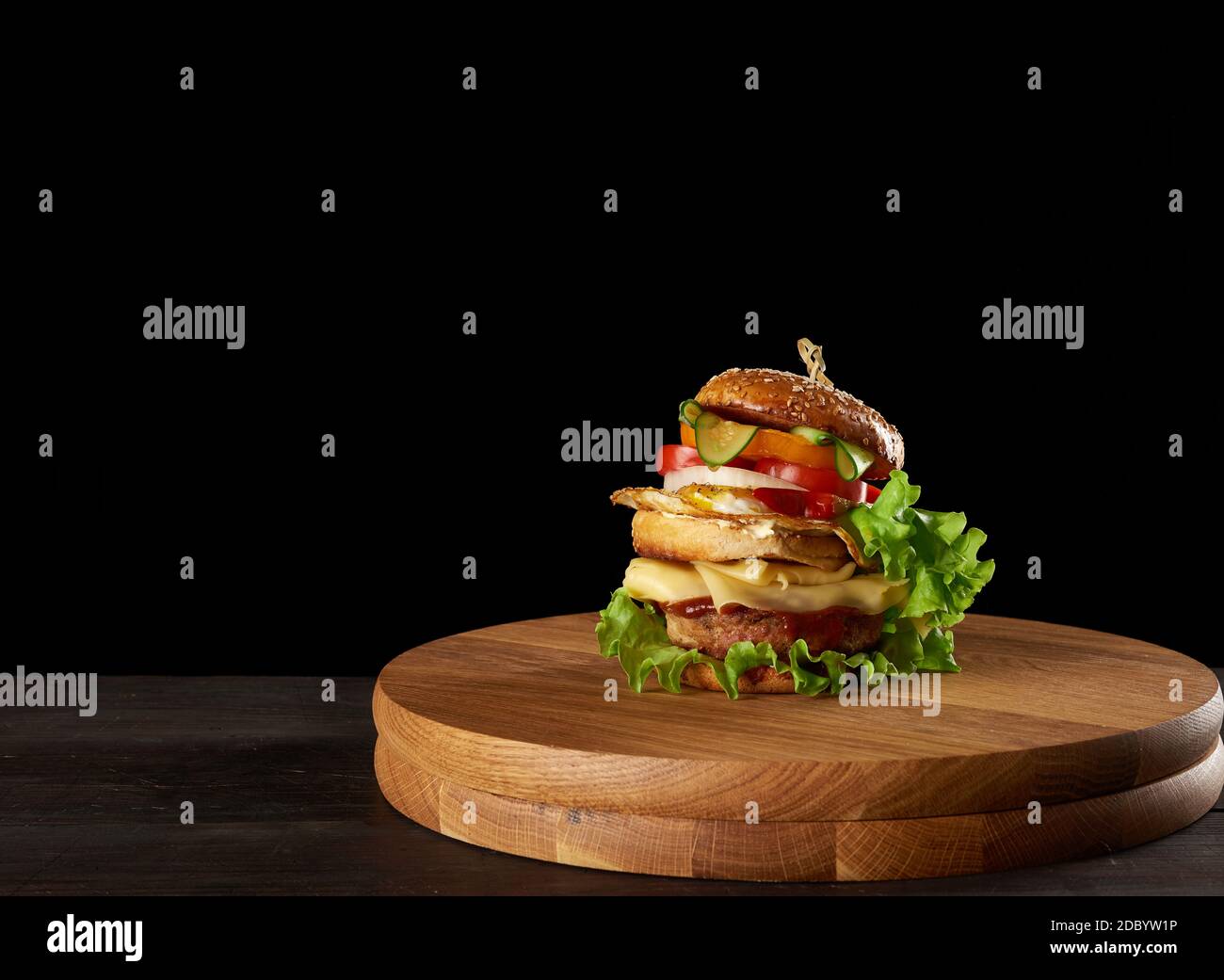 big delicious burger with meat cutlet, cheese, fried egg, tomatoes ...