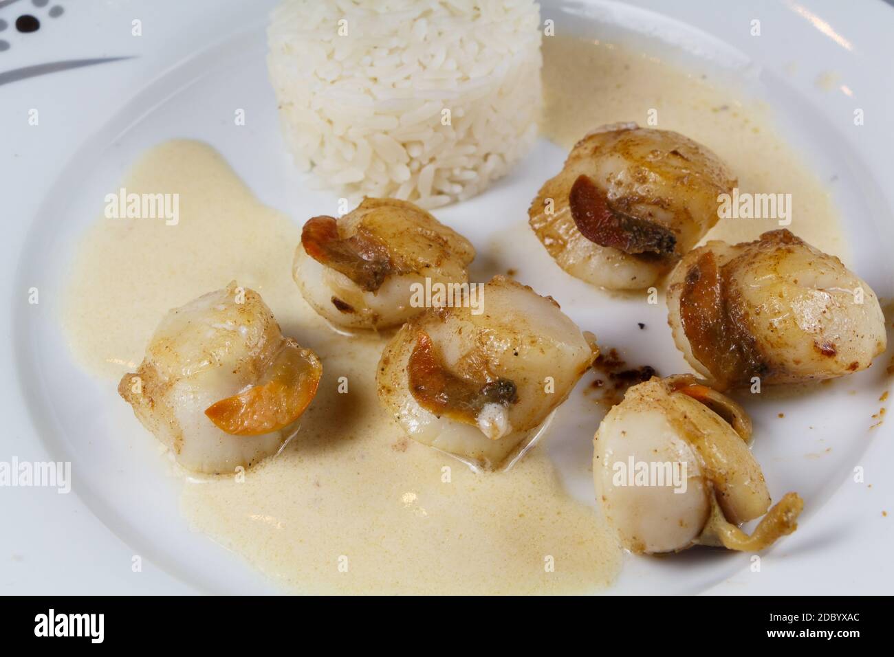 Plate of grilled scallops with rice and cream sauce Stock Photo - Alamy