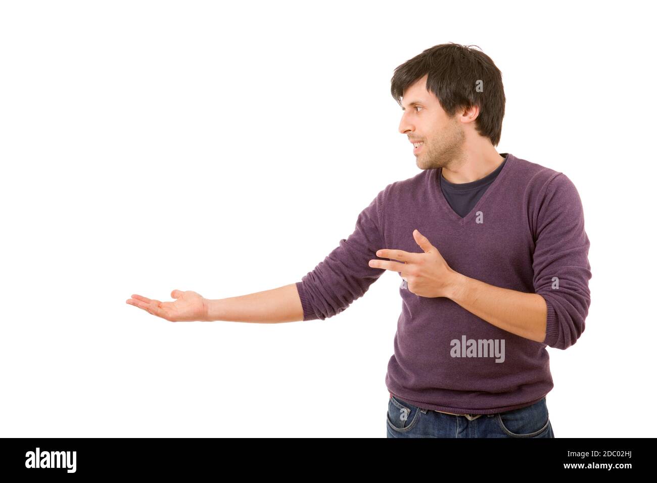 friendly young man pointing to his side and looking into the camera ...