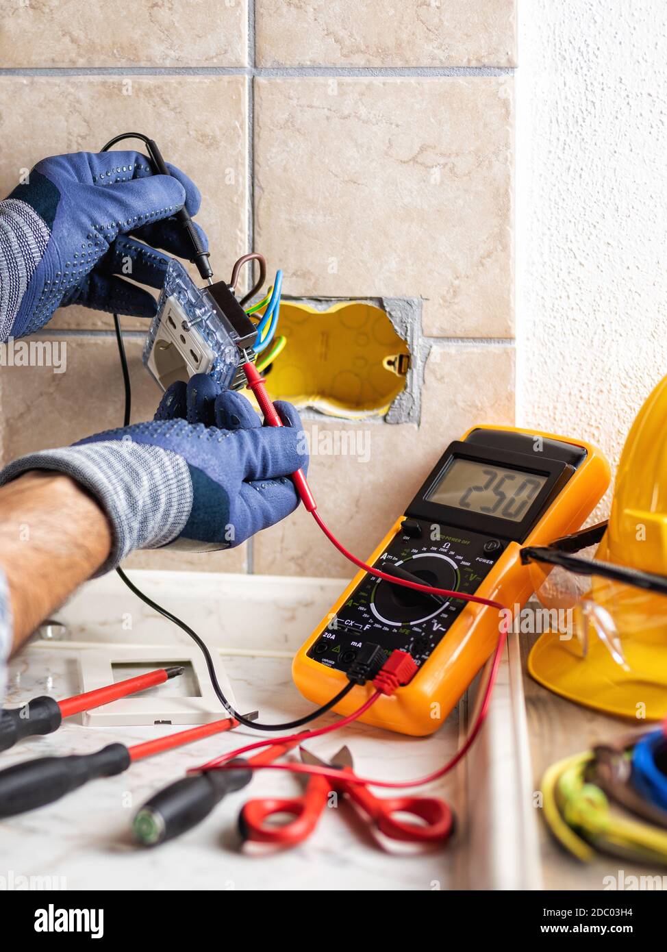 Electrician at work with the tester measures the voltage in the sockets ...