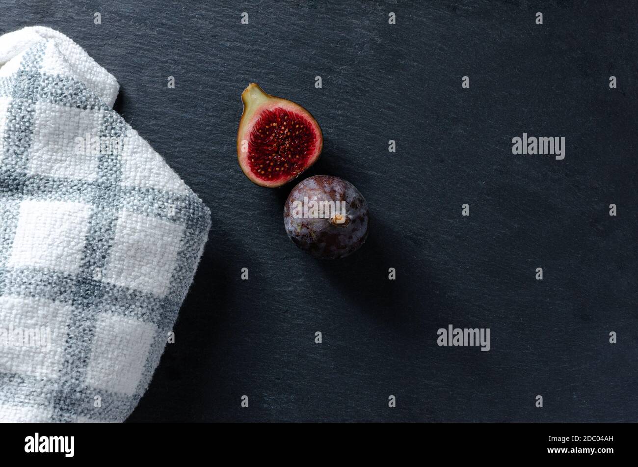 Still life of black figs with a knife and a cloth on a slate base ...